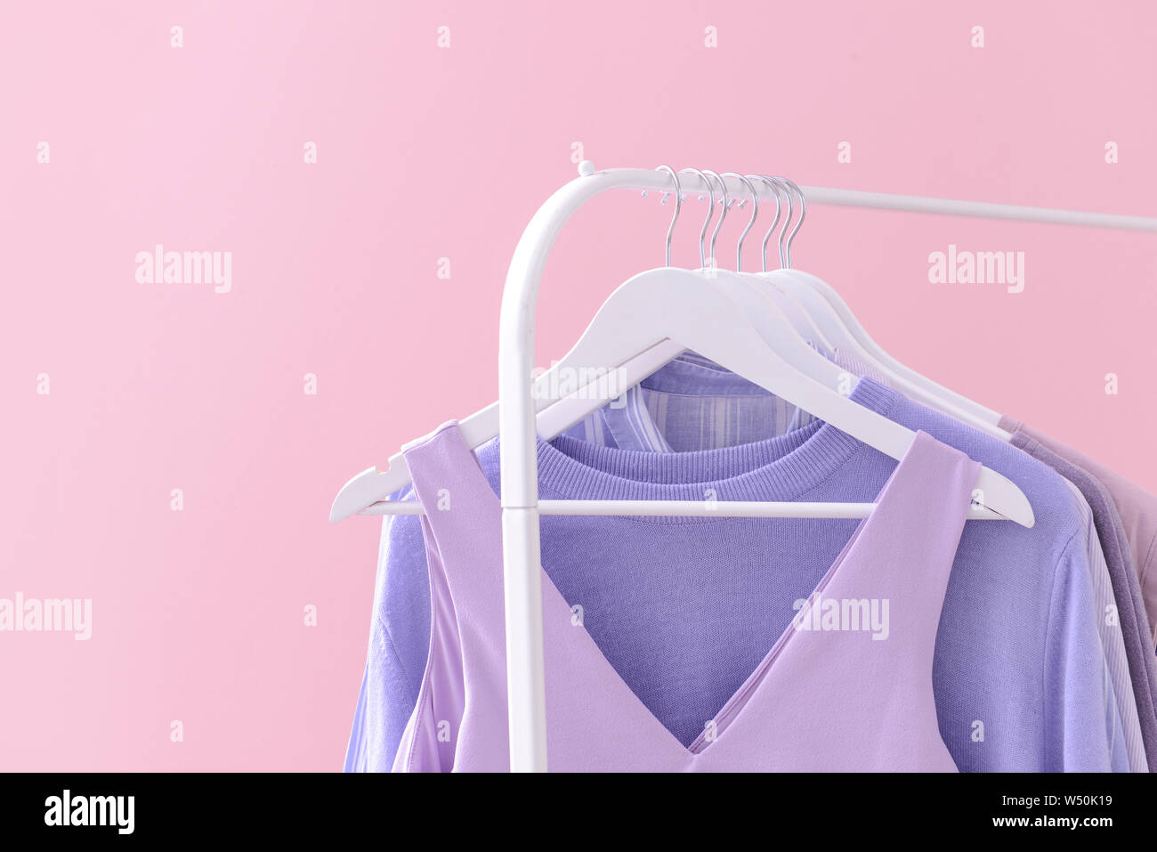 Rack with hanging clothes on color background Stock Photo - Alamy