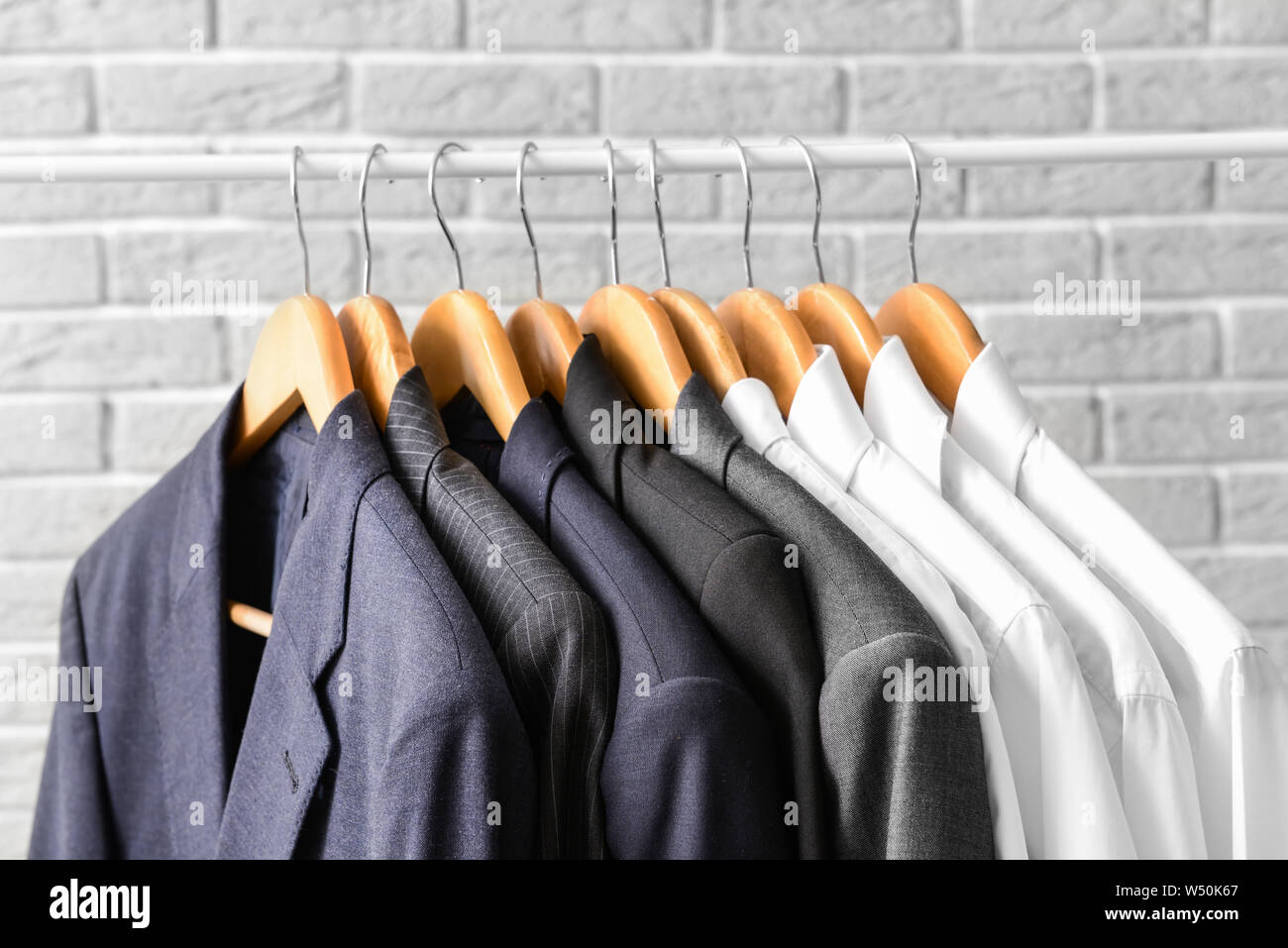 Rack with hanging clothes against brick wall Stock Photo - Alamy