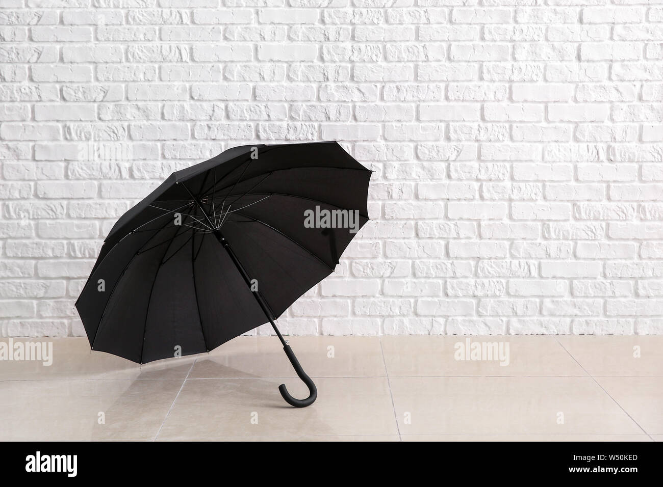Stylish umbrella near white brick wall Stock Photo - Alamy