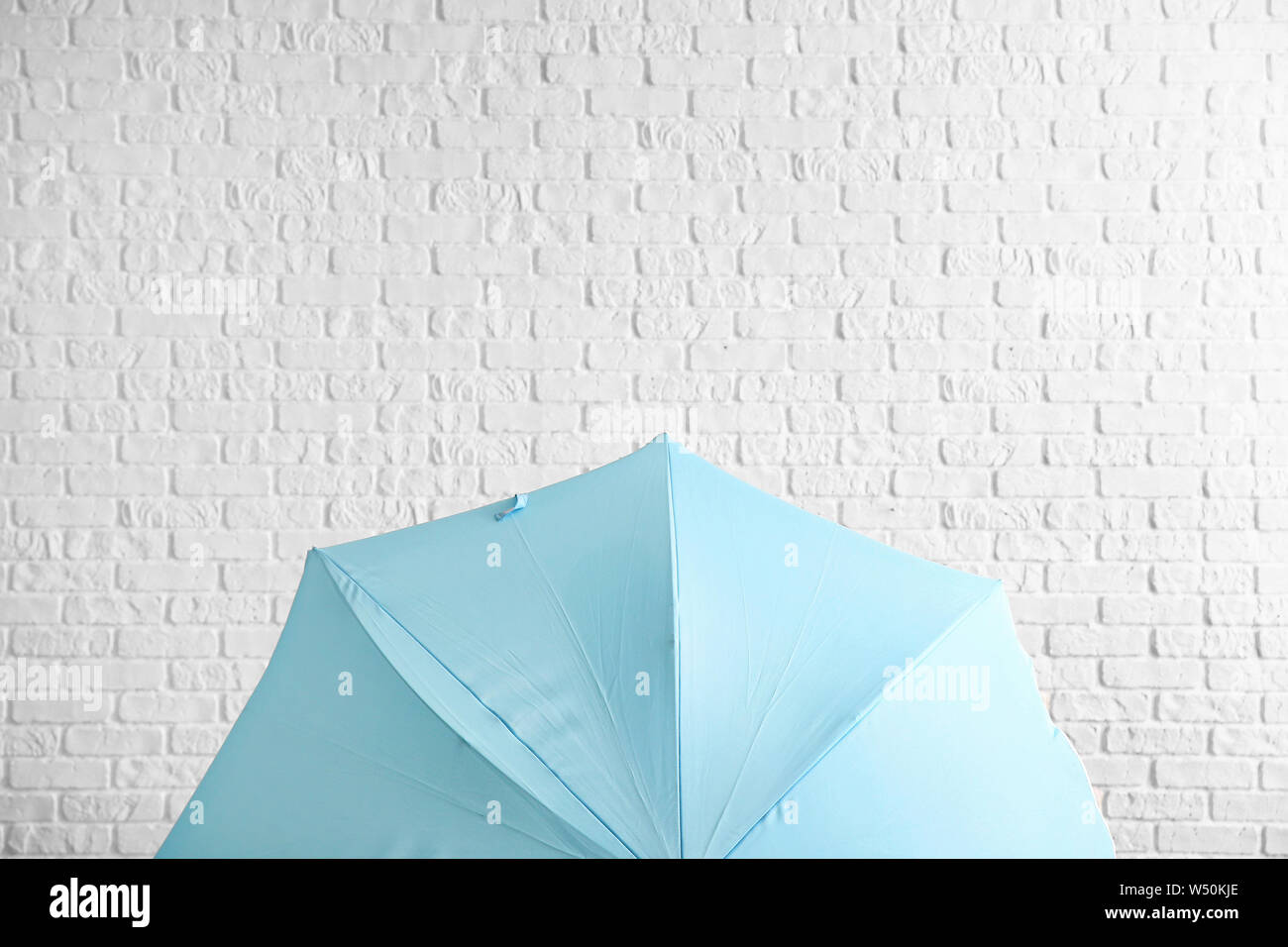 Stylish umbrella near white brick wall Stock Photo - Alamy