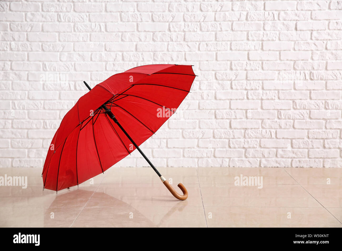 Stylish umbrella near white brick wall Stock Photo - Alamy