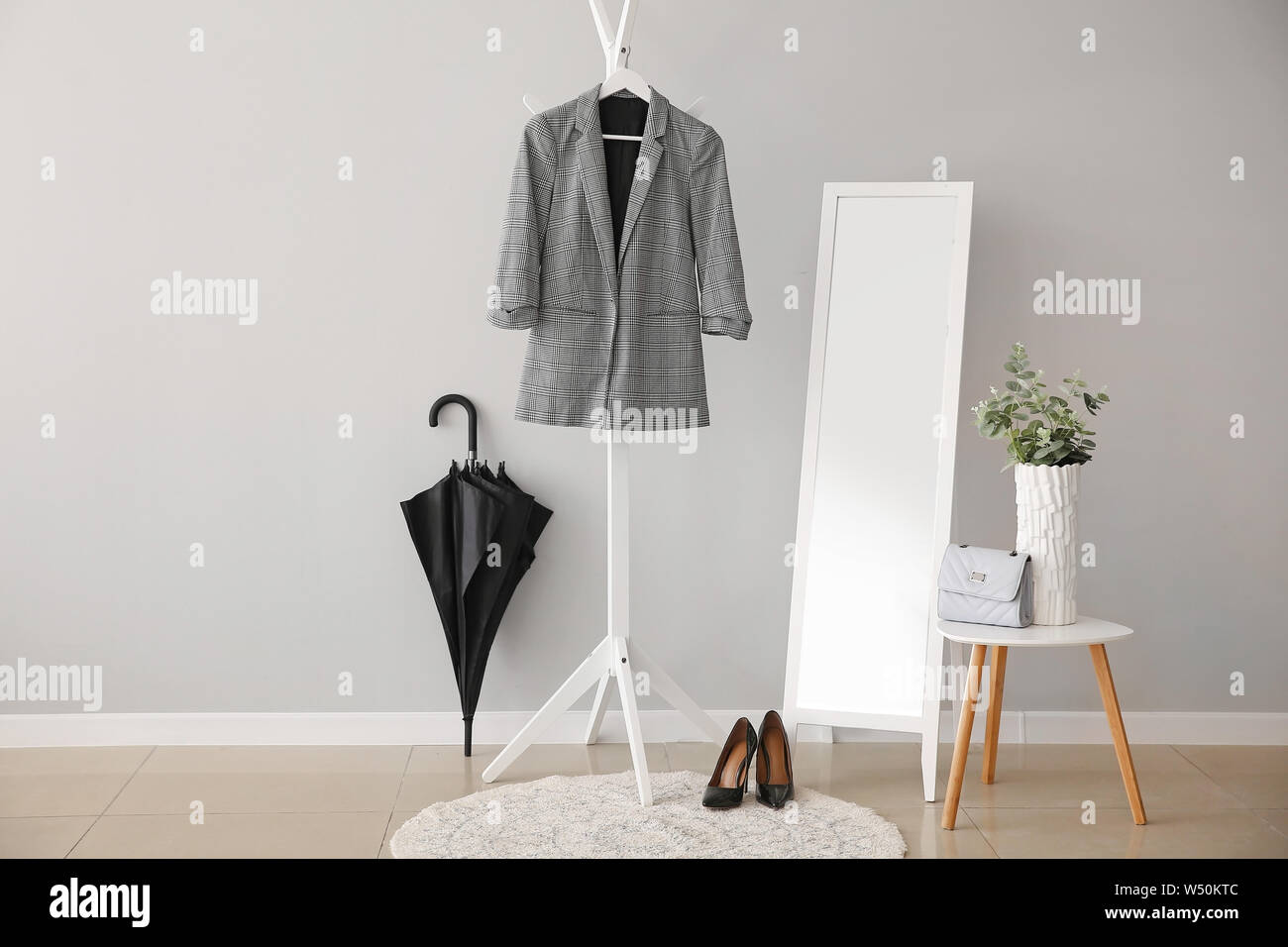 Stylish umbrella with clothes in interior of hall Stock Photo - Alamy