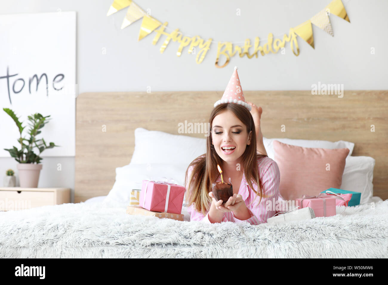 Happy woman with Birthday cake lying on bed at home Stock Photo - Alamy