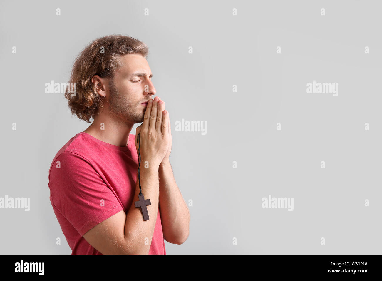 Religious young man praying on light background Stock Photo - Alamy