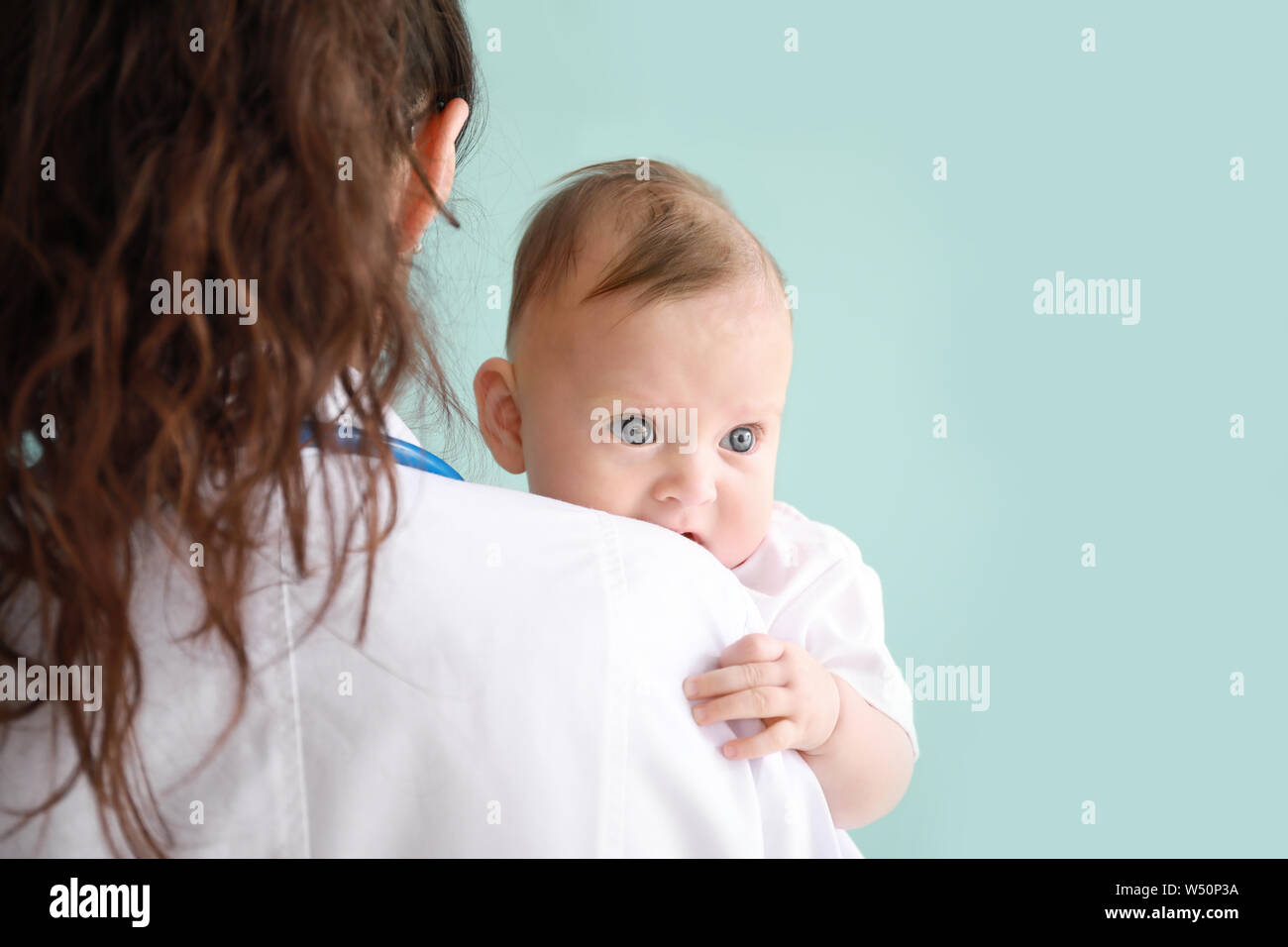 Pediatrician with cute little baby on color background Stock Photo - Alamy