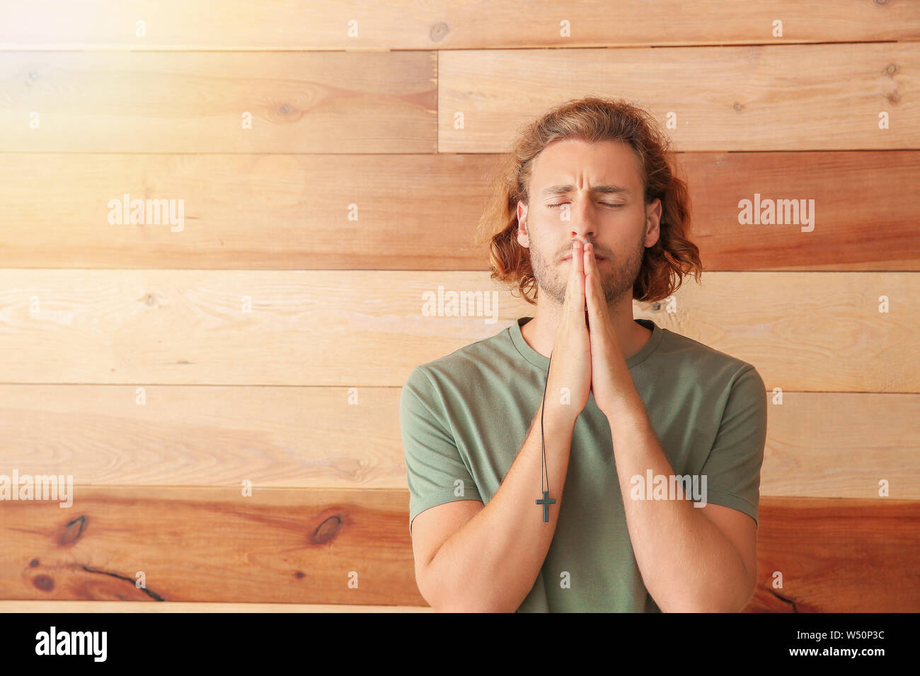 Religious young man praying on wooden background Stock Photo - Alamy