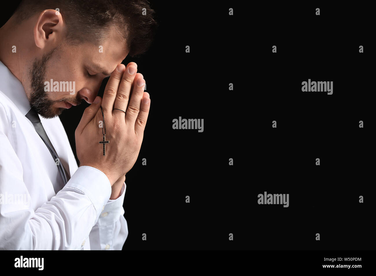 Religious man praying on dark background Stock Photo - Alamy
