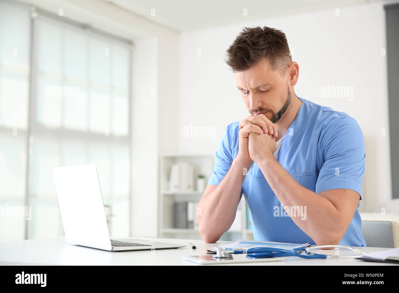 Religious doctor praying in clinic Stock Photo - Alamy