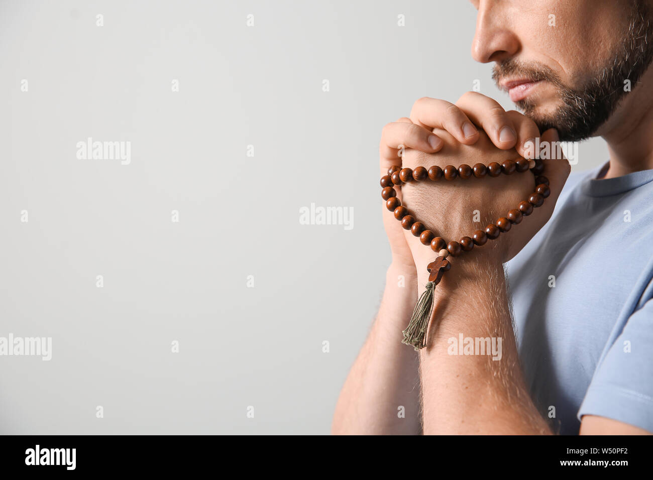 Religious man praying on light background Stock Photo - Alamy