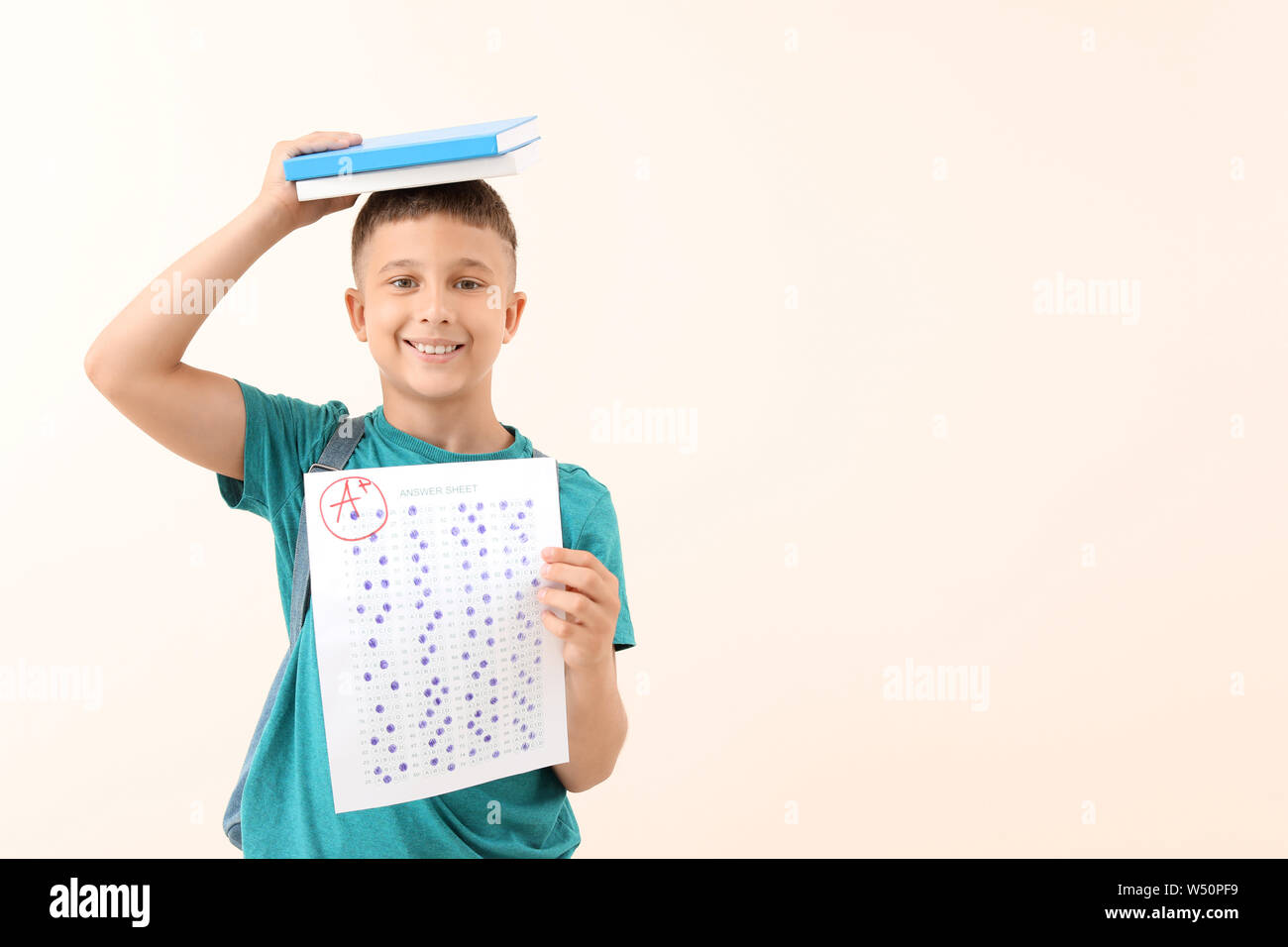 Happy boy with answer sheet for school test on light background Stock ...