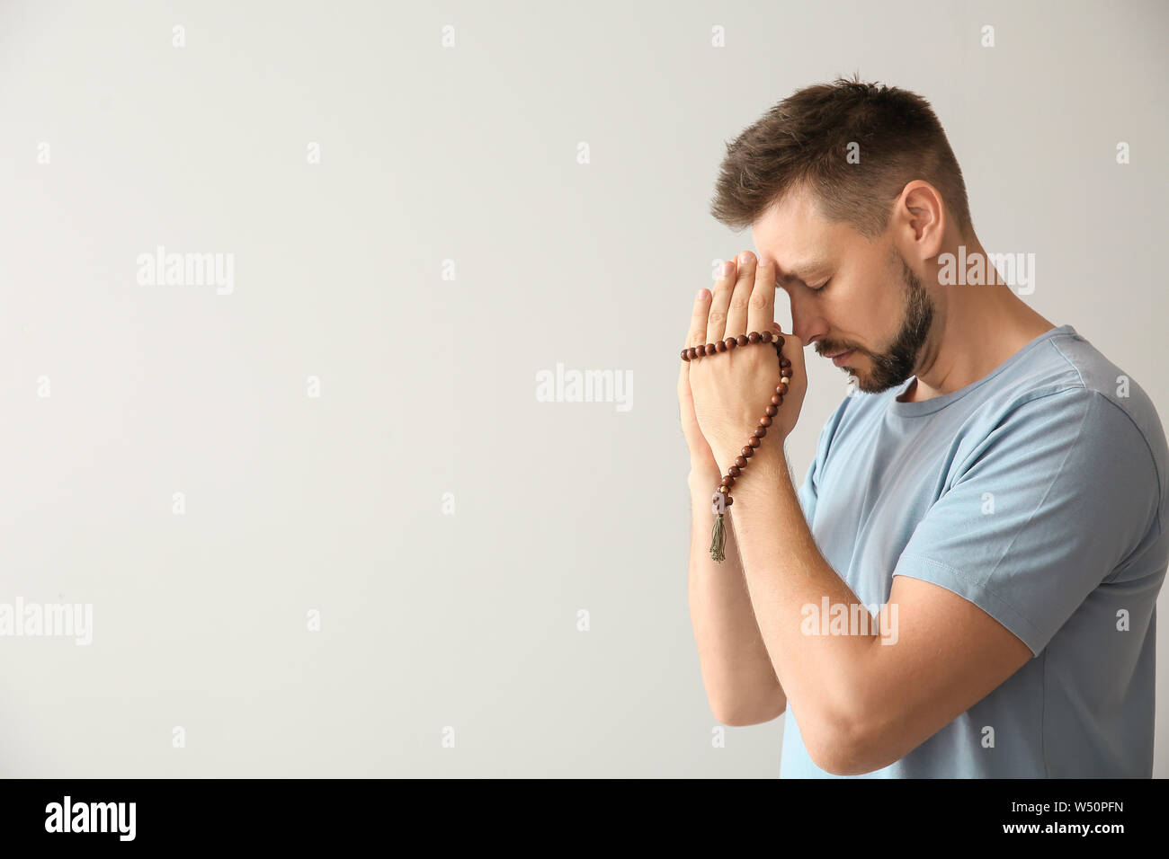 Religious man praying on light background Stock Photo - Alamy