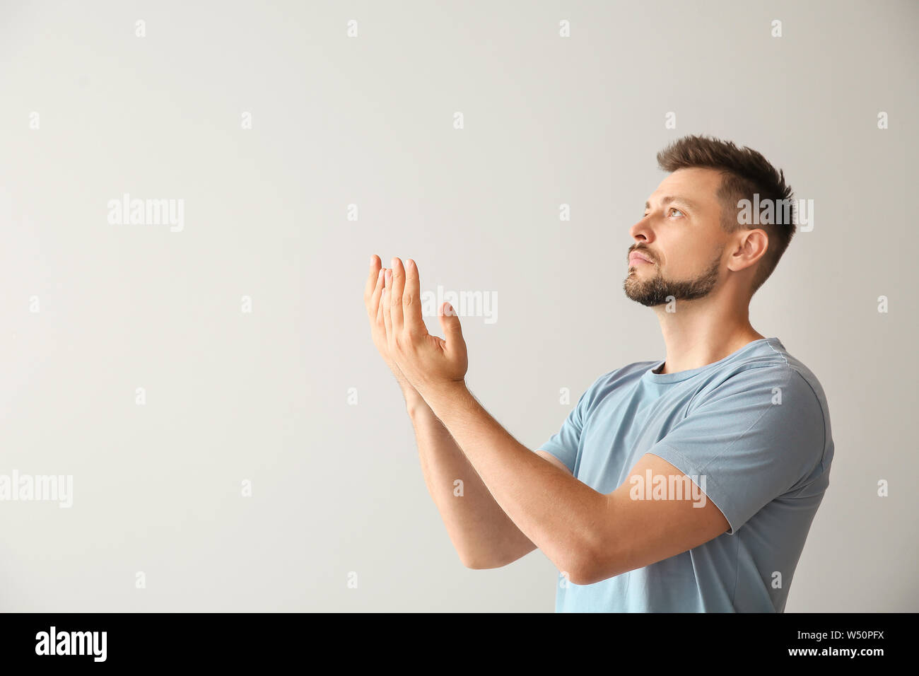 Religious man praying on light background Stock Photo - Alamy