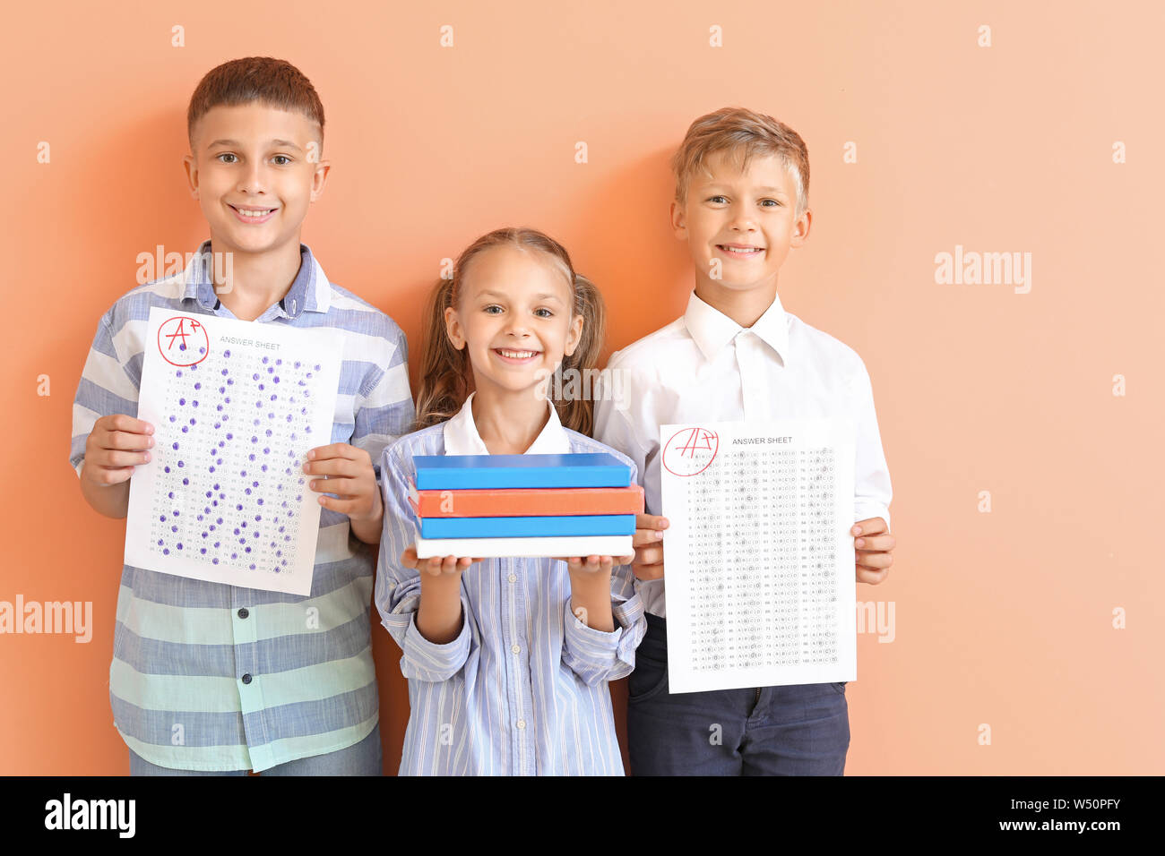 Happy children with answer sheets for school test on color background ...