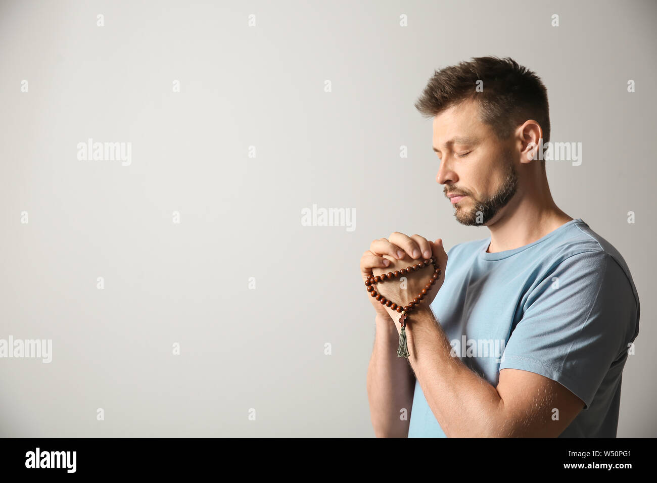 Religious man praying on light background Stock Photo - Alamy