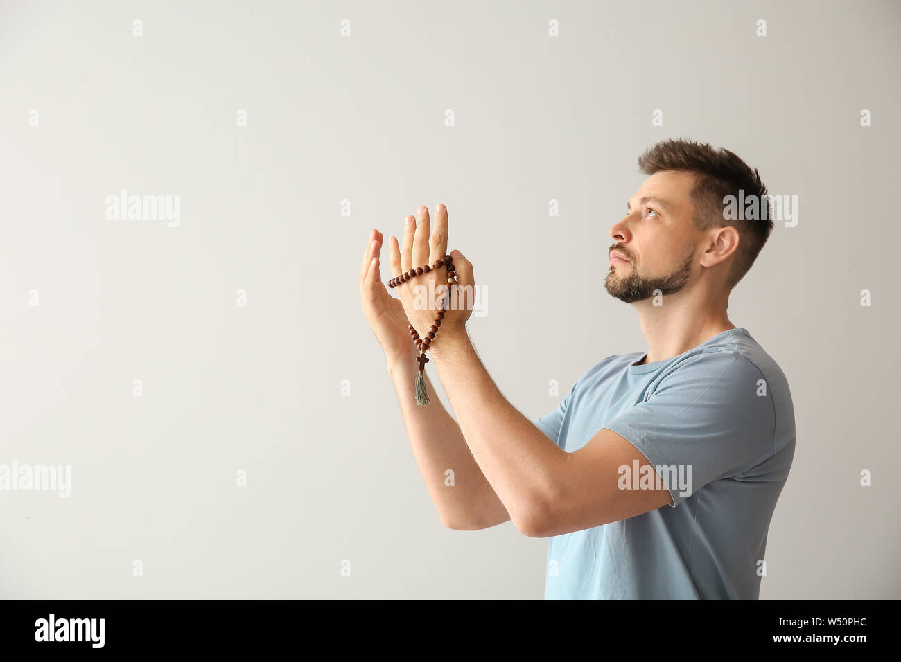Religious man praying on light background Stock Photo - Alamy