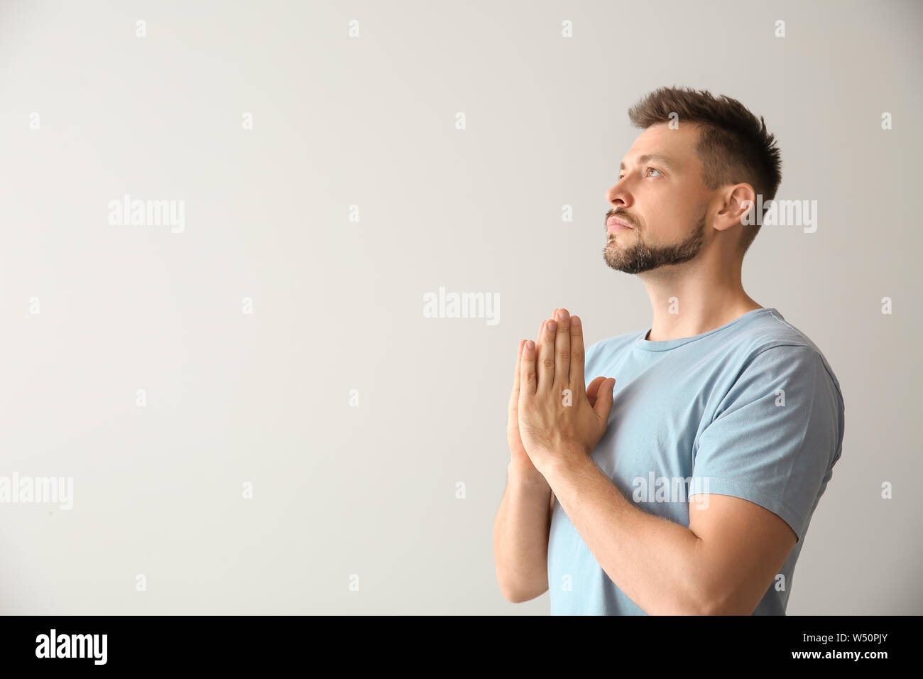 Religious man praying on light background Stock Photo - Alamy