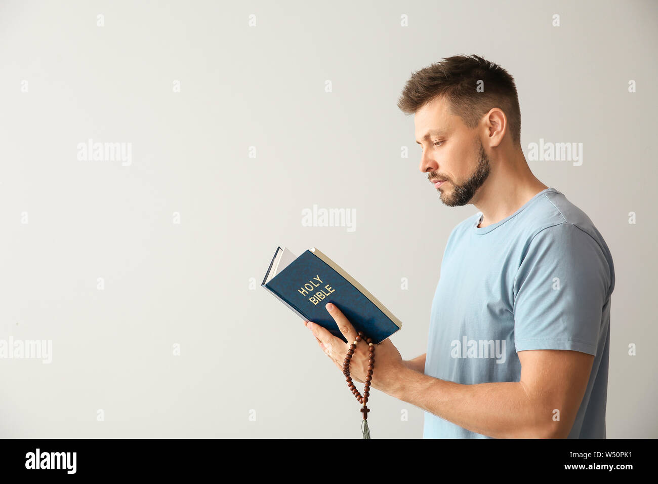 Religious man reading Bible on light background Stock Photo - Alamy