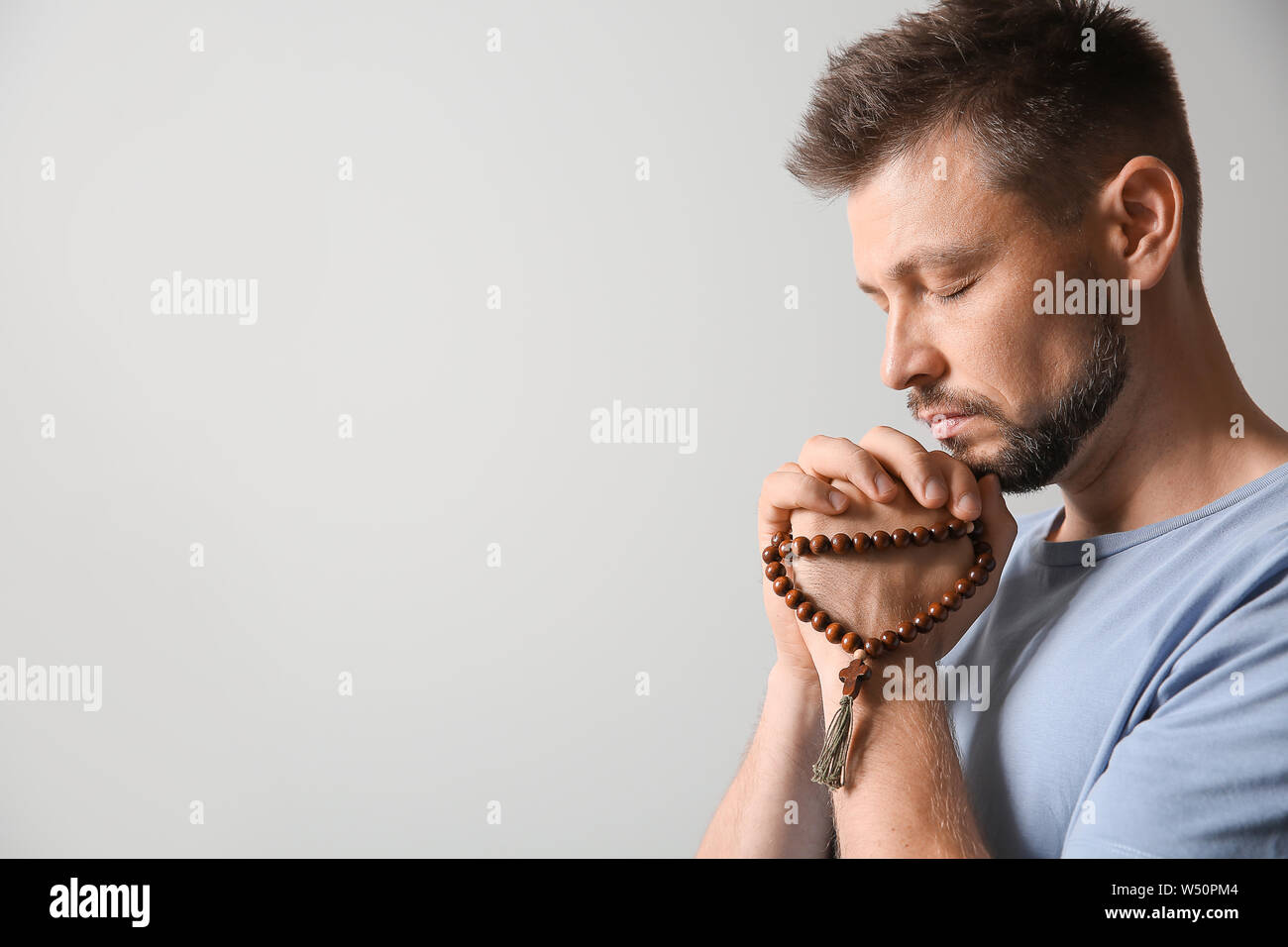 Religious man praying on light background Stock Photo - Alamy
