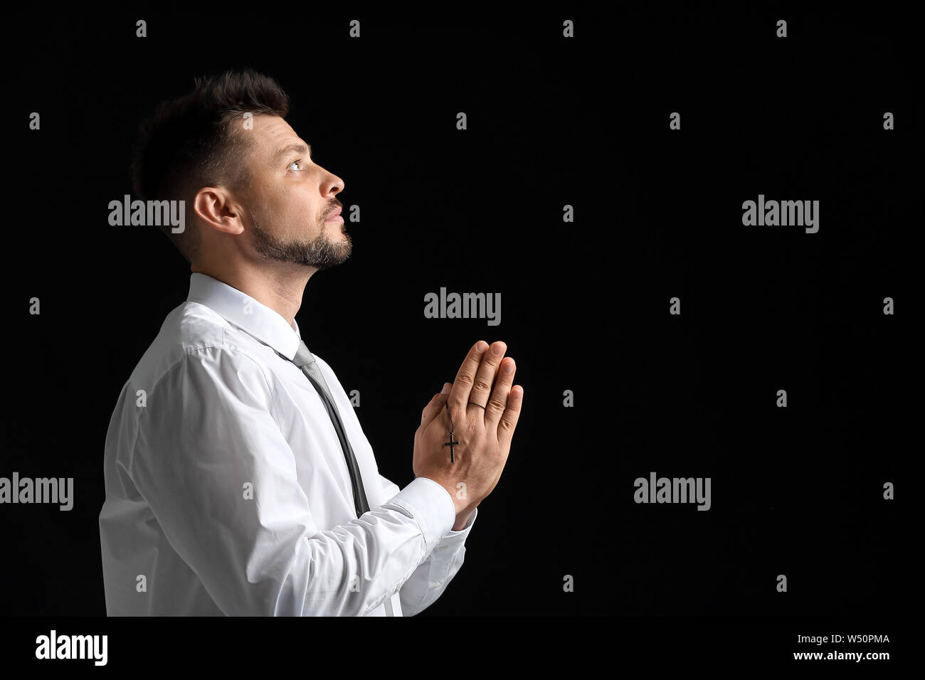 Religious man praying on dark background Stock Photo - Alamy
