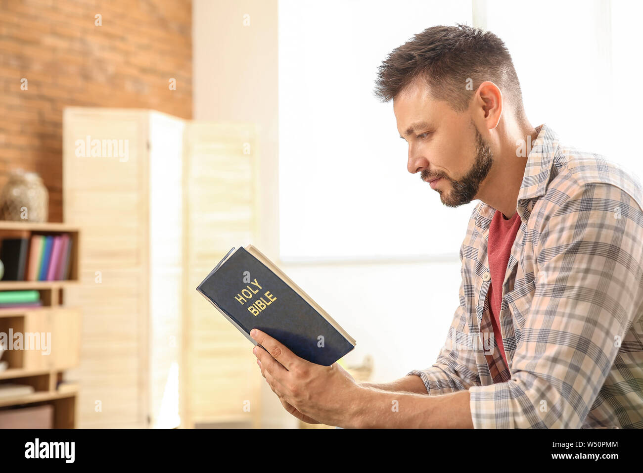 Religious man reading Bible at home Stock Photo - Alamy