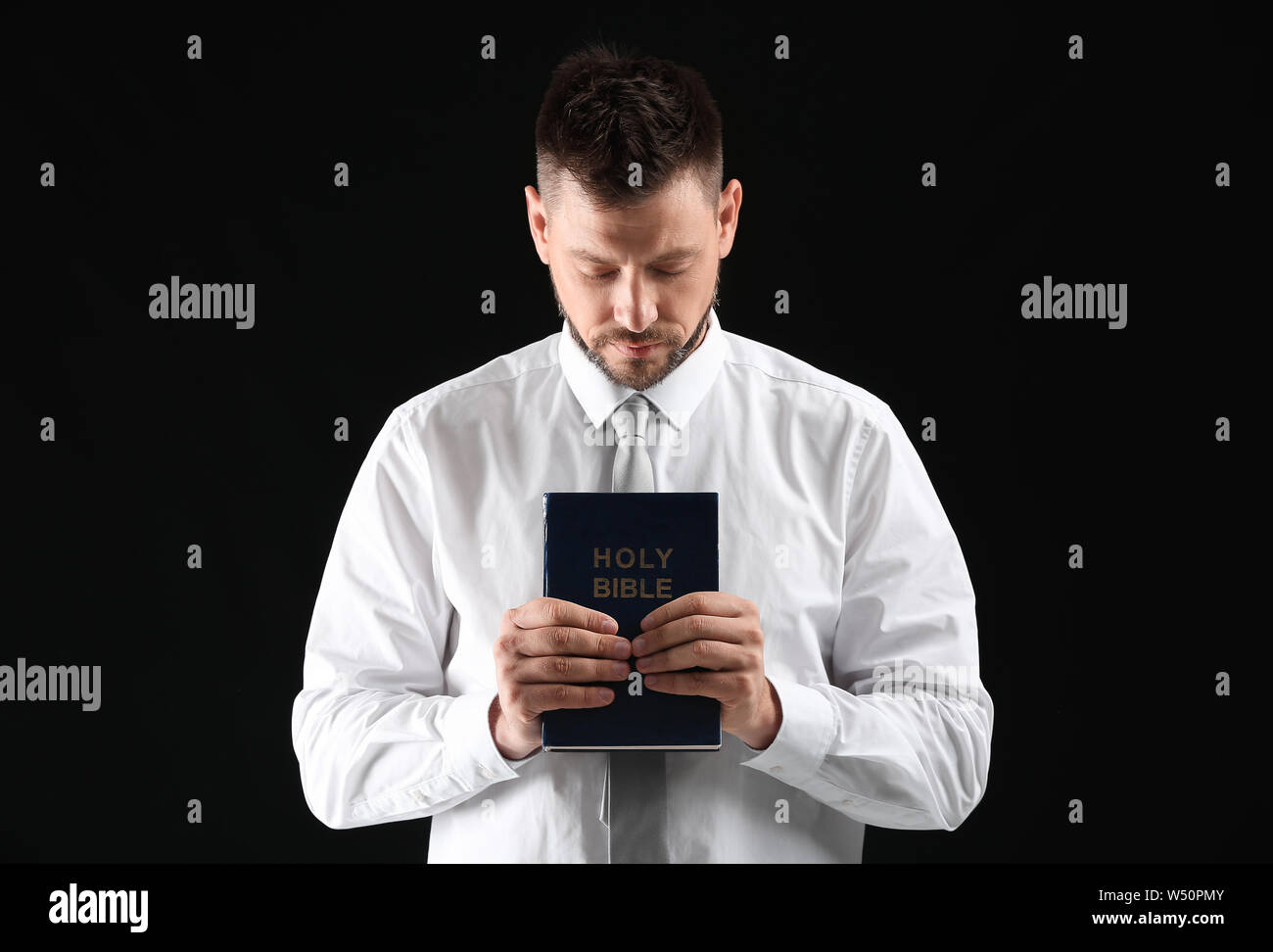 Religious man praying on dark background Stock Photo - Alamy