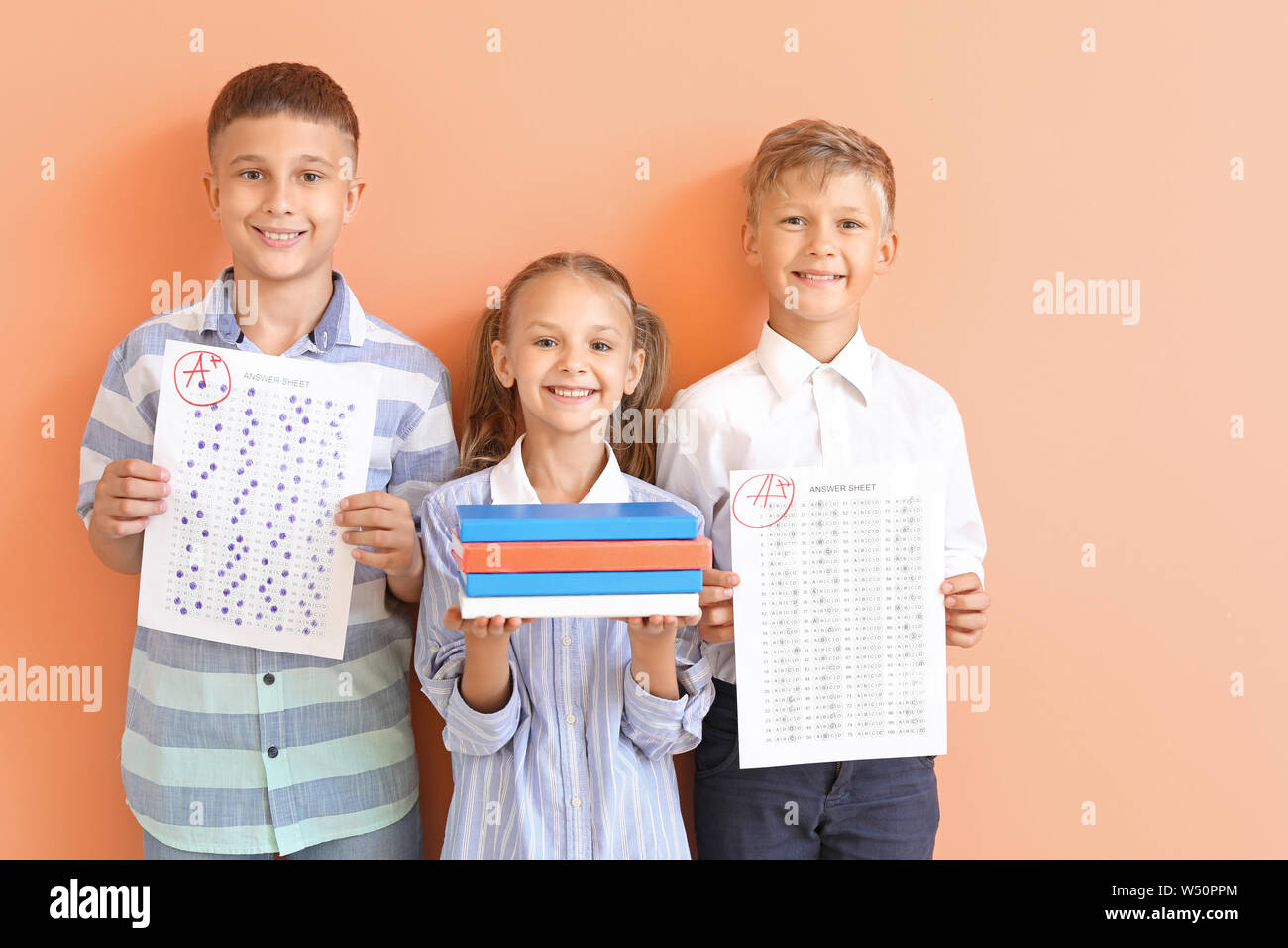 Happy children with answer sheets for school test on color background ...