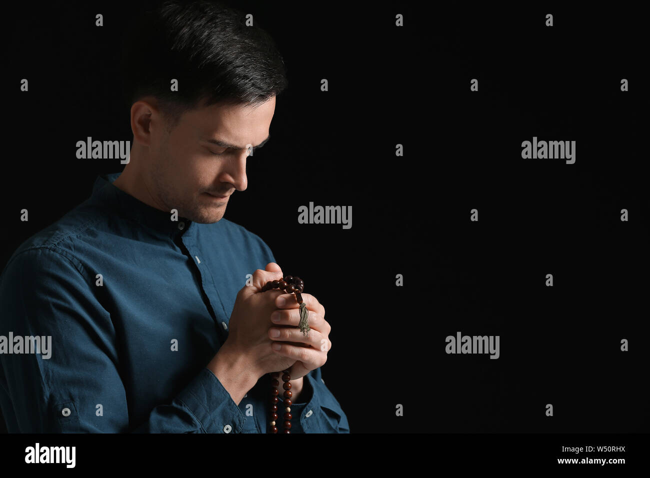 Religious man praying to God on dark background Stock Photo - Alamy