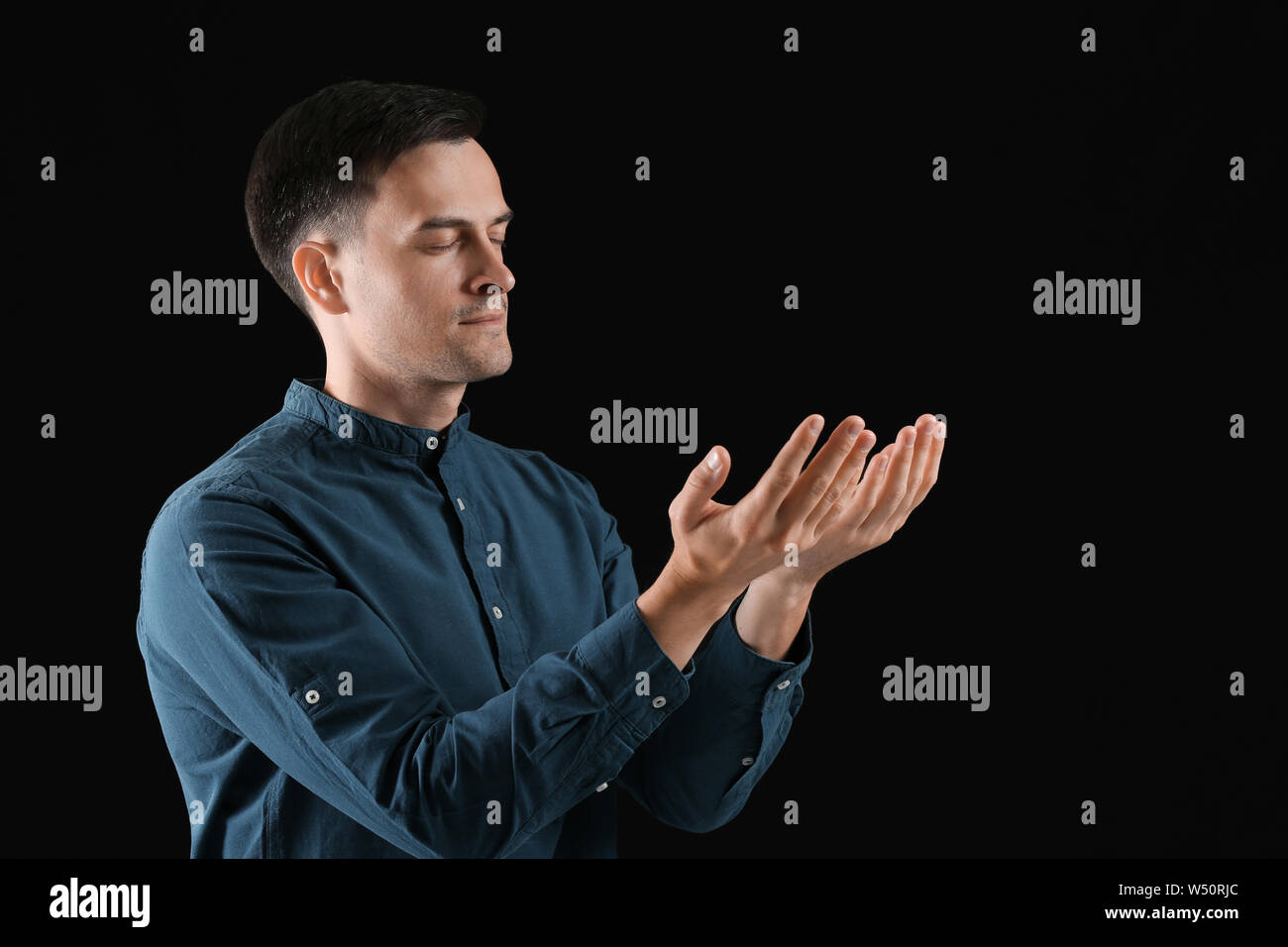Religious man praying to God on dark background Stock Photo - Alamy