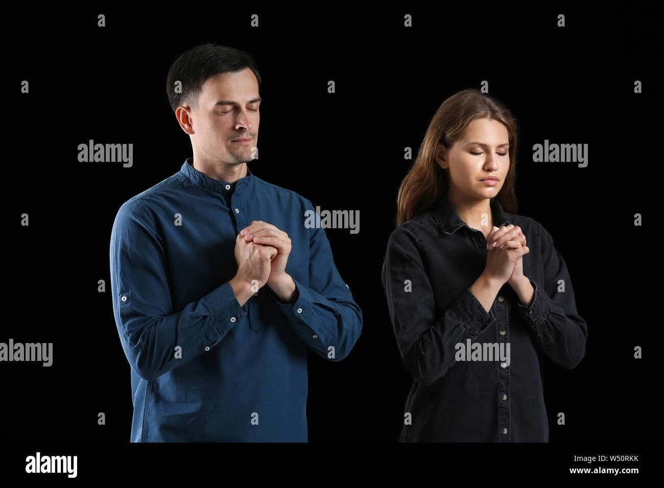 Religious couple praying to God on dark background Stock Photo - Alamy
