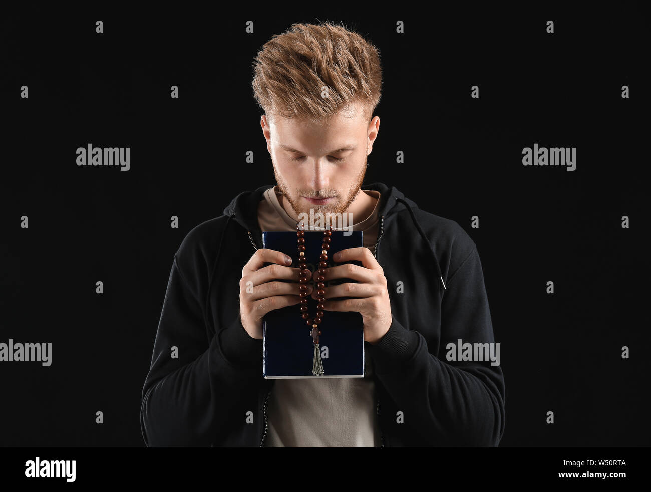 Religious young man praying to God on dark background Stock Photo - Alamy