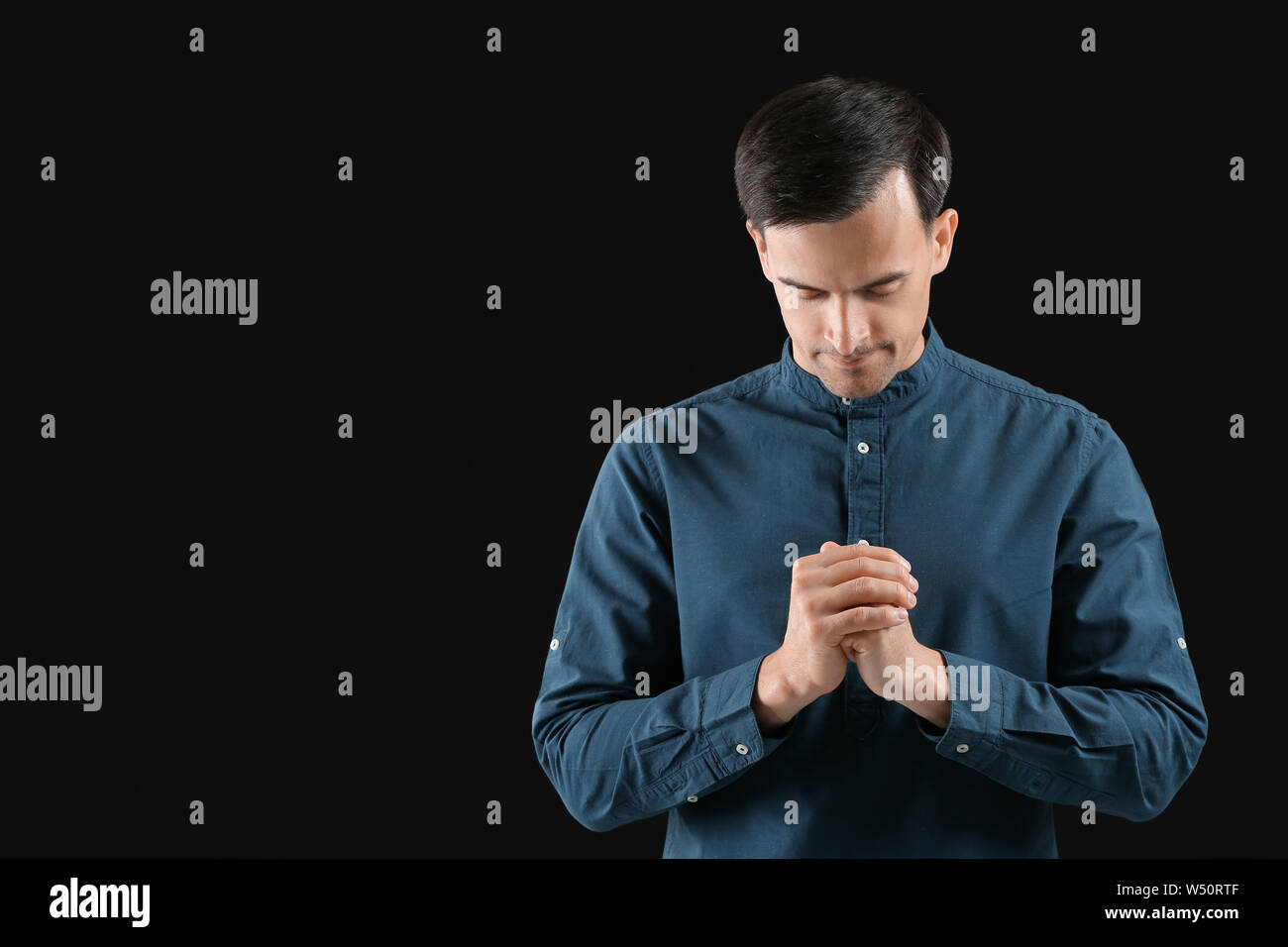 Religious man praying to God on dark background Stock Photo - Alamy