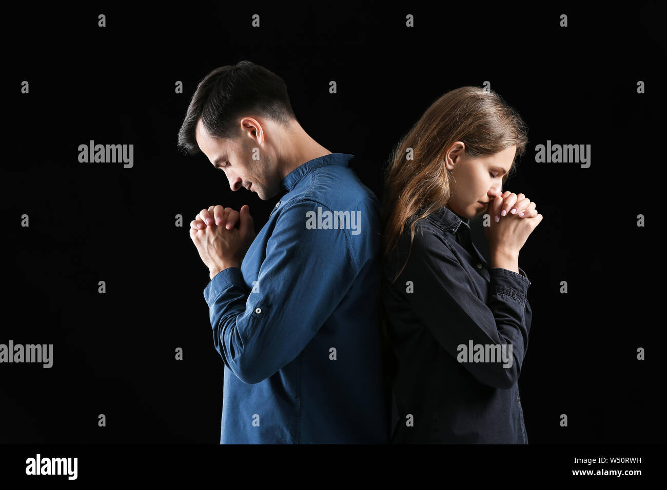 Religious couple praying to God on dark background Stock Photo - Alamy