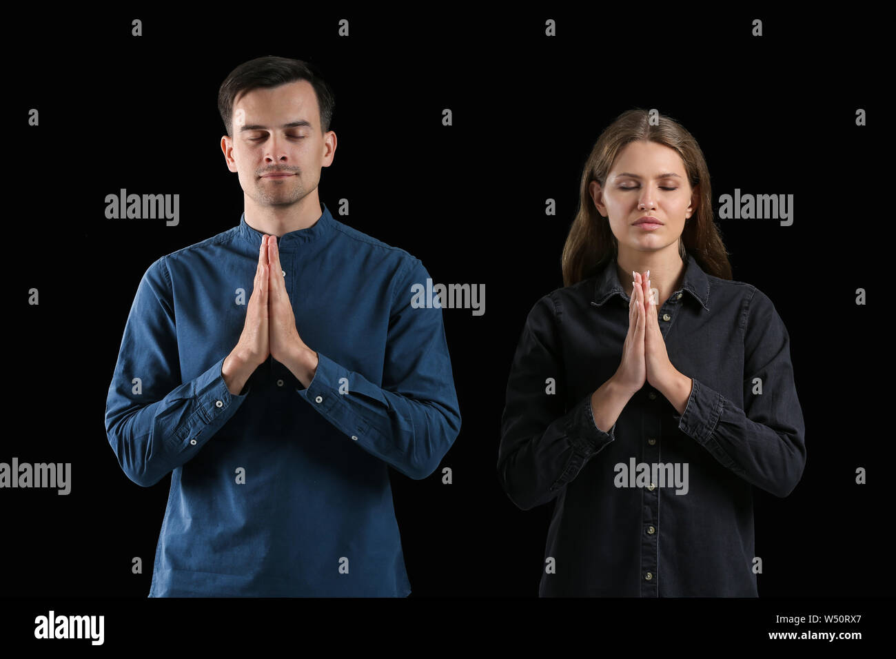 Religious couple praying to God on dark background Stock Photo - Alamy