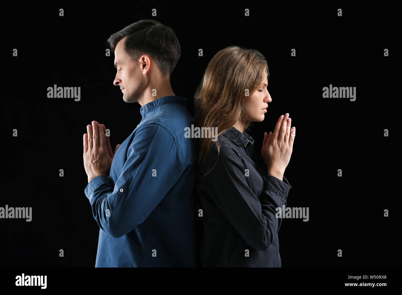 Religious couple praying to God on dark background Stock Photo - Alamy