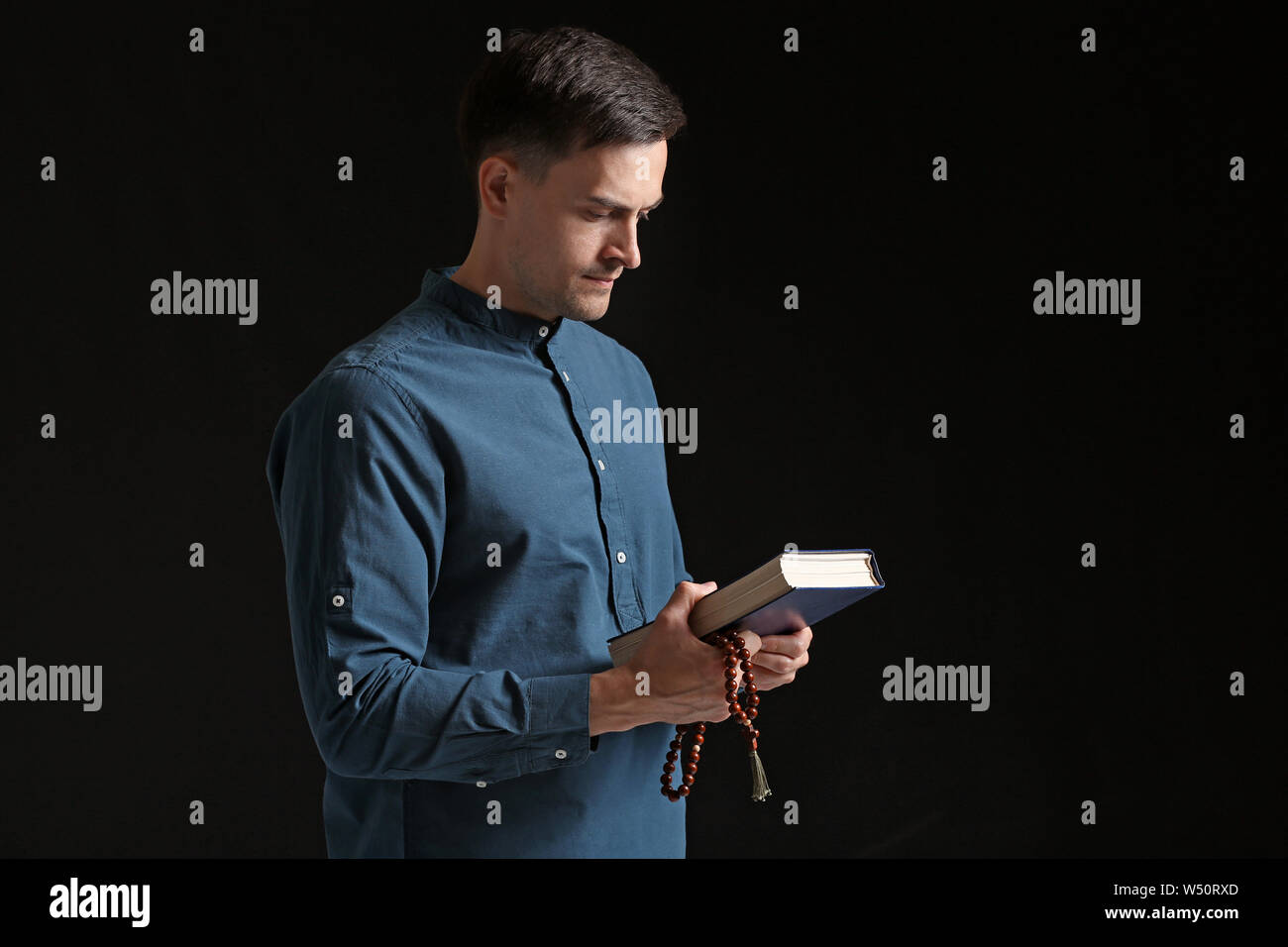 Religious man praying to God on dark background Stock Photo - Alamy