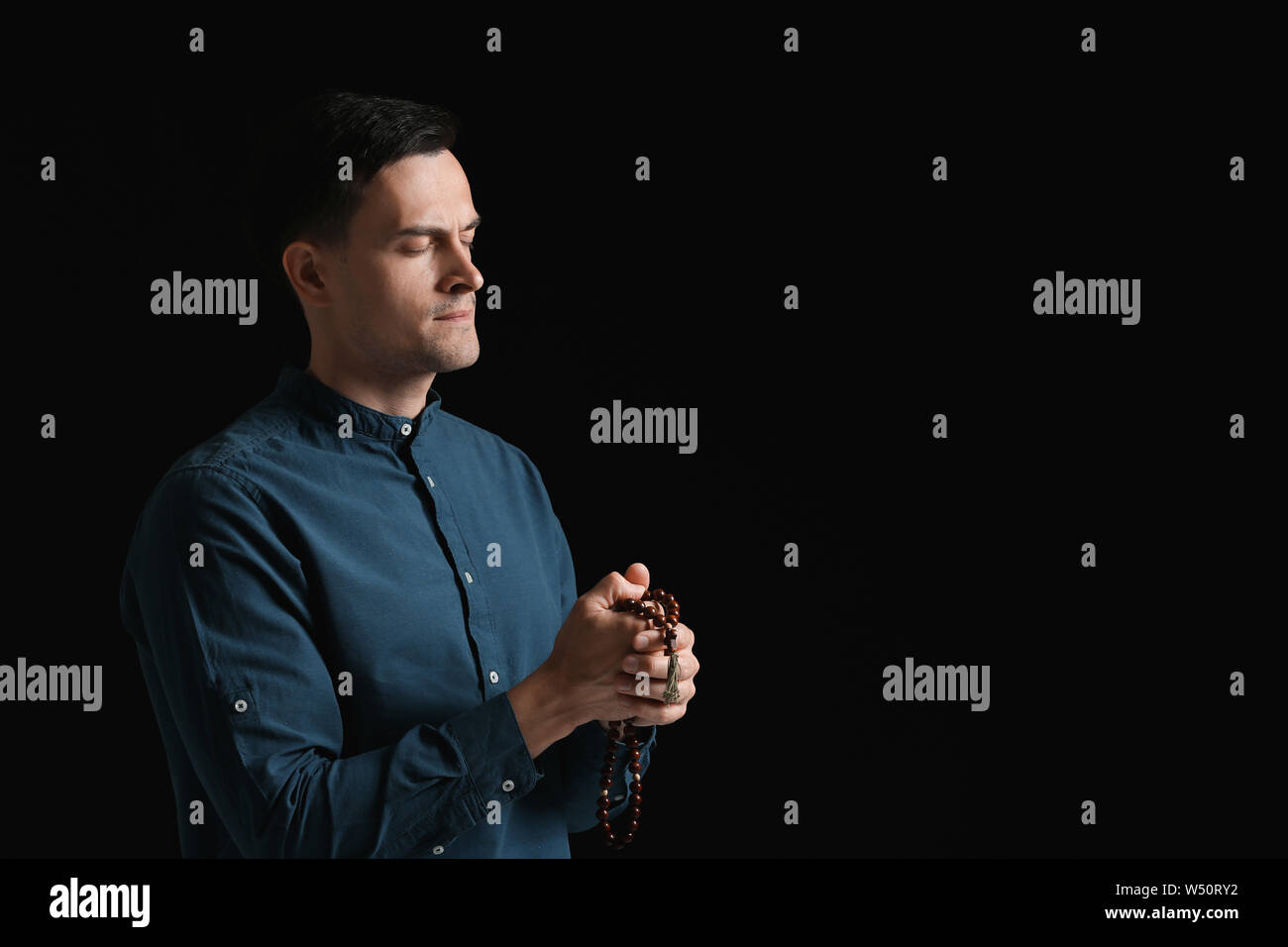 Religious man praying to God on dark background Stock Photo - Alamy