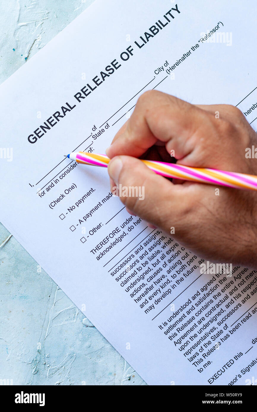 The person filling General Release of Liability form paper on bright ...