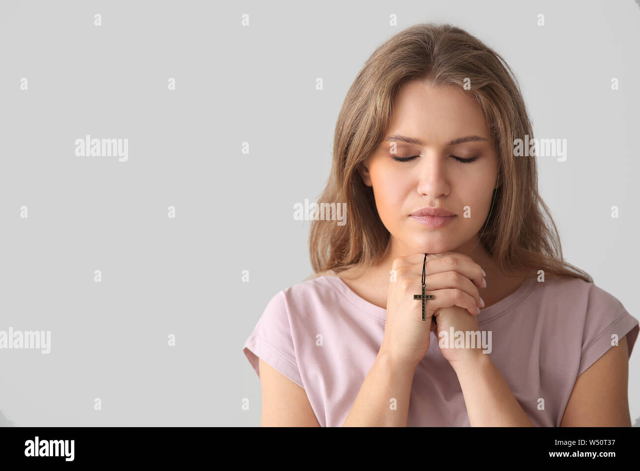 Religious young woman praying to God on light background Stock Photo ...
