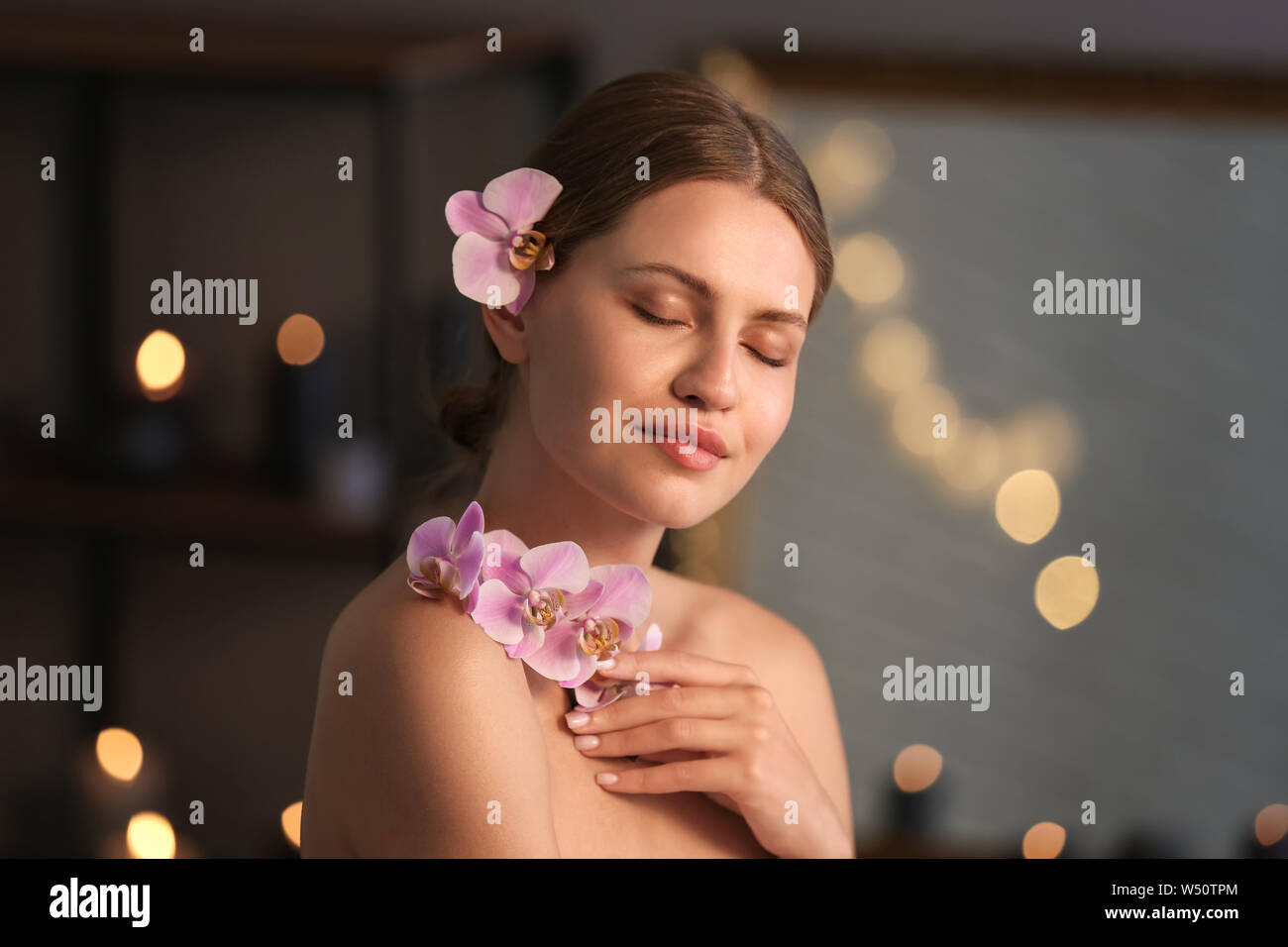 Beautiful young woman with orchid flowers in spa salon Stock Photo - Alamy