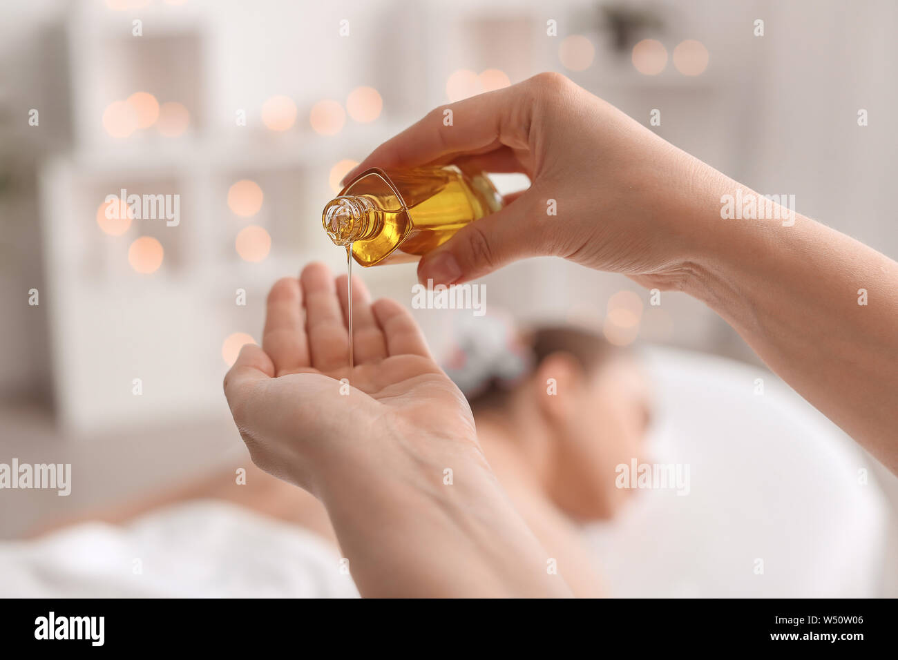 Massage therapist pouring essential oil onto hand in spa salon Stock ...