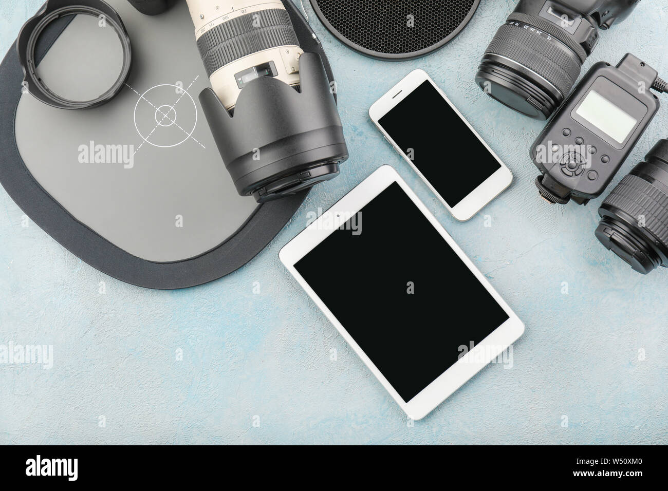 Tablet computer and set of photographer's equipment on light background ...