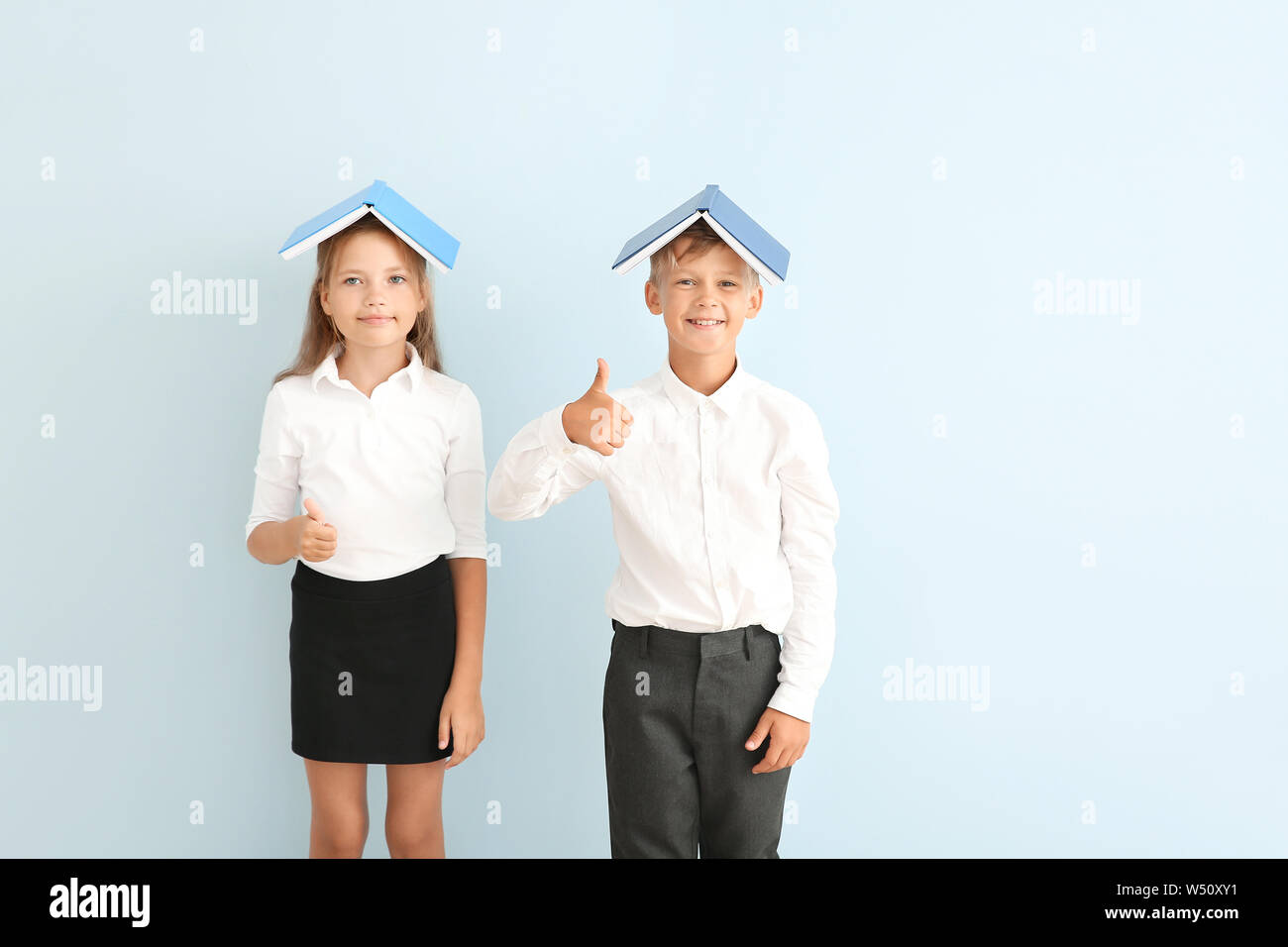 Little pupils with books showing thumb-up on color background Stock ...