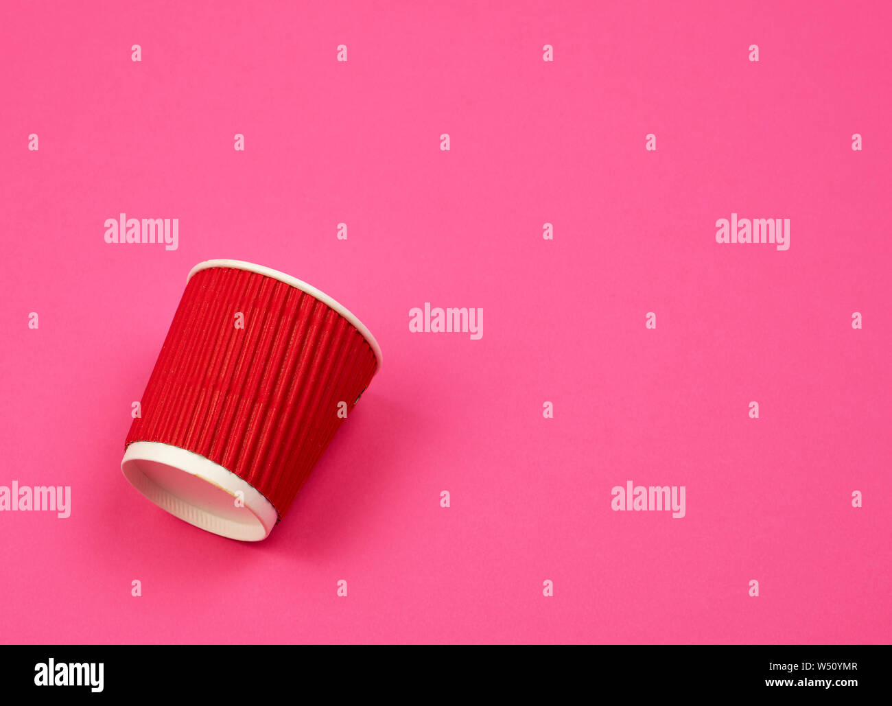 red paper cup with corrugated edges for hot drinks on a pink background ...