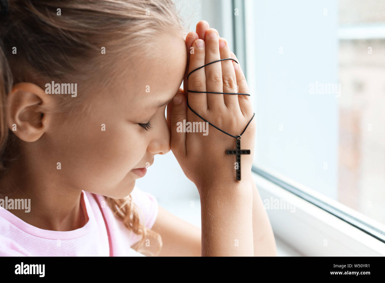 Praying little girl near window Stock Photo - Alamy