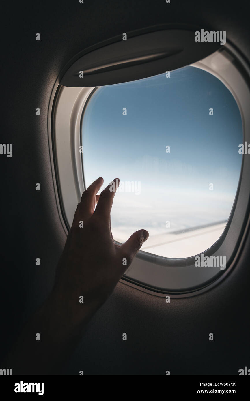 Porthole window in the plane with a man's hand during the flight Stock ...