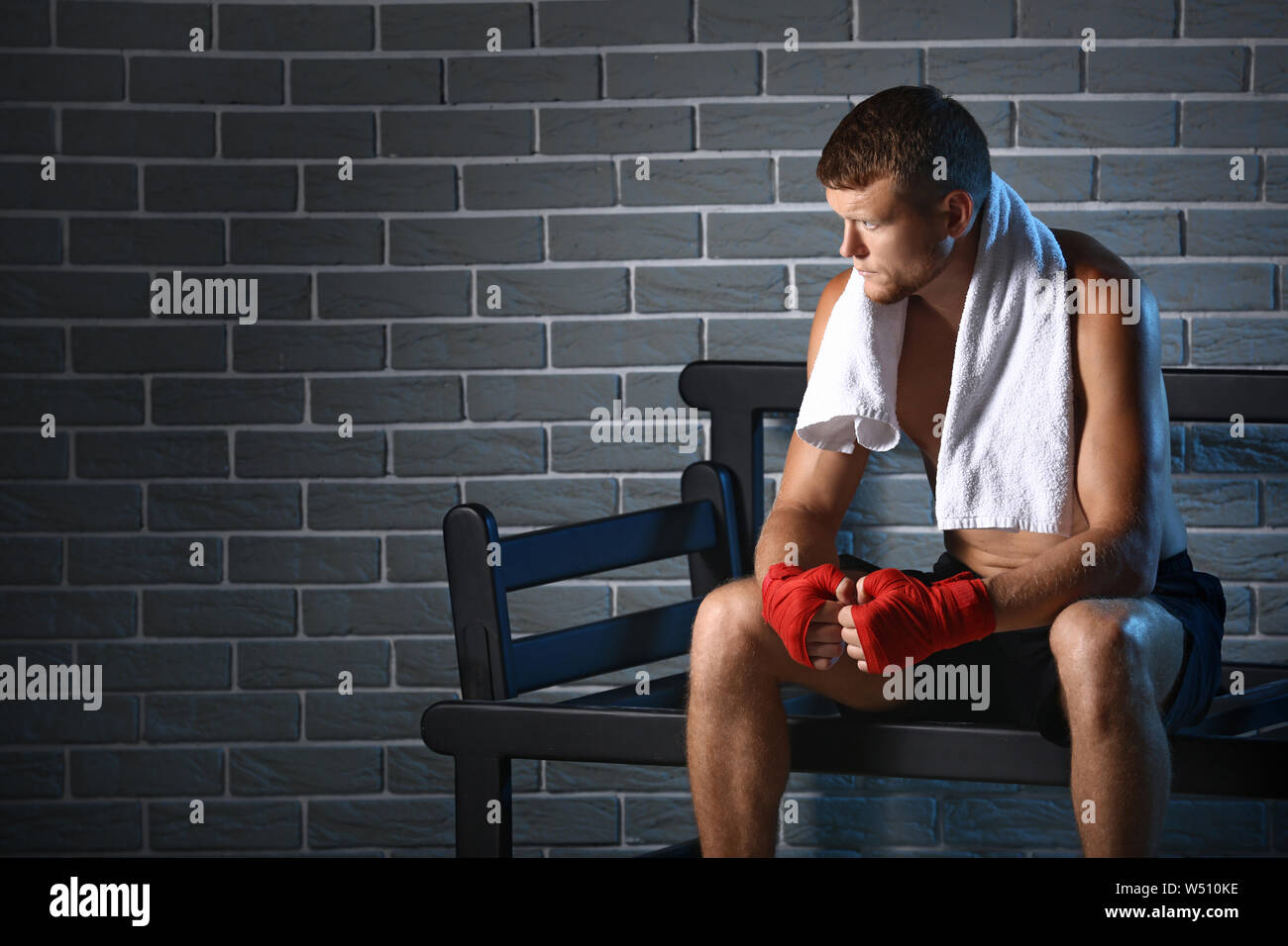Strong male boxer sitting on bench against brick wall Stock Photo - Alamy