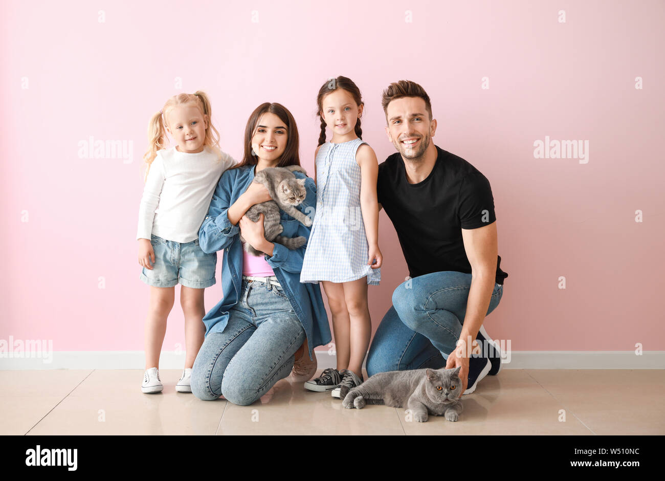 Happy family with cute cats near color wall Stock Photo - Alamy