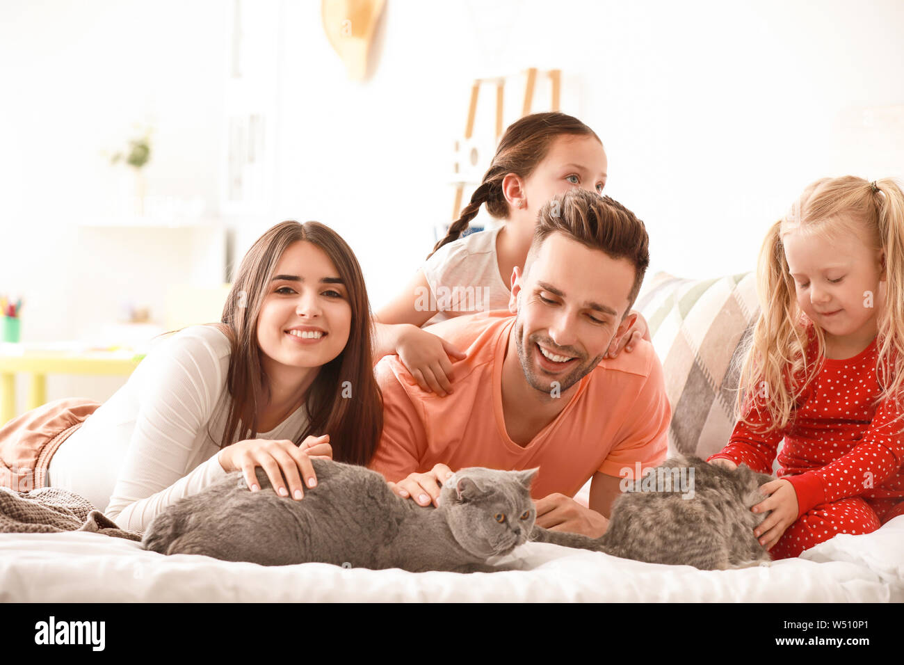 Happy family with cute cats on bed at home Stock Photo - Alamy