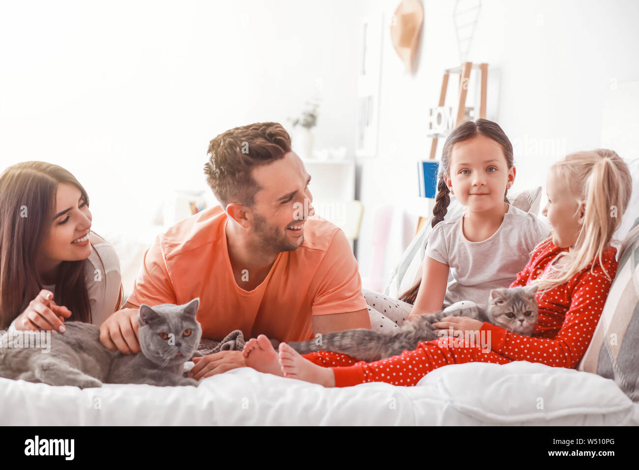 Happy family with cute cats on bed at home Stock Photo - Alamy