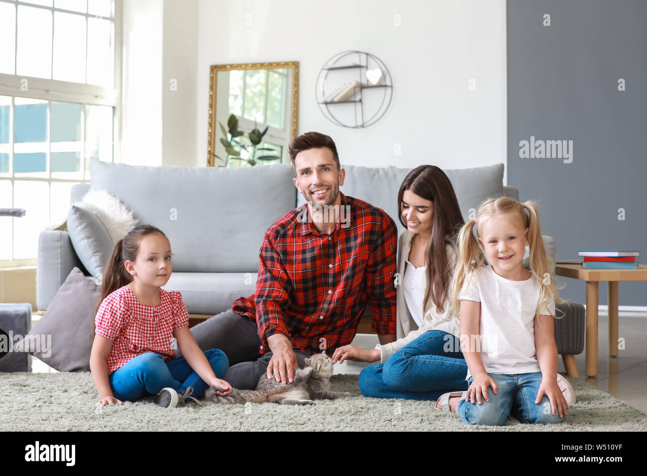 Happy family with cute cat resting at home Stock Photo - Alamy